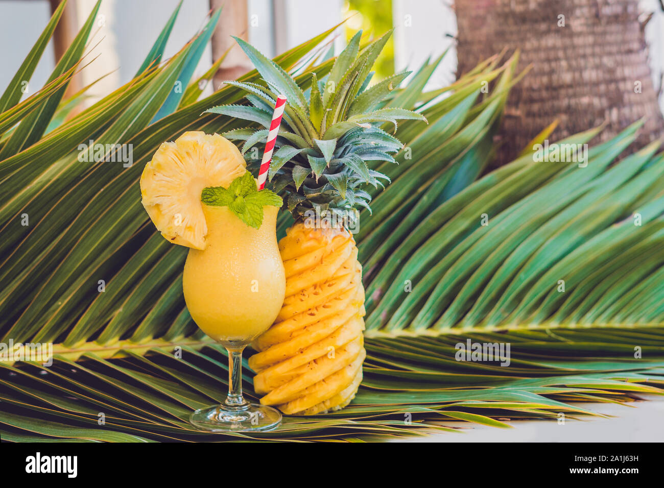 Pineapple and pineapple smoothies against the background of a branch of ...