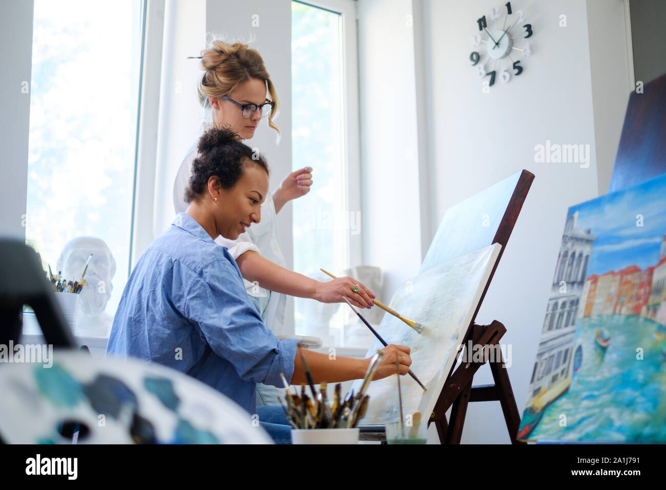 Creative painter and her protege working in a studio Stock Photo - Alamy