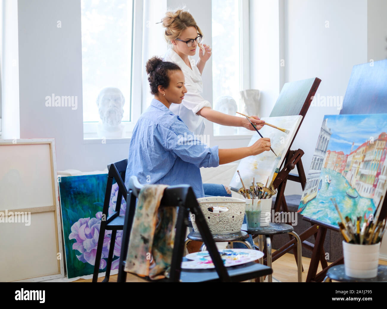 Creative painter and her protege working in a studio Stock Photo - Alamy