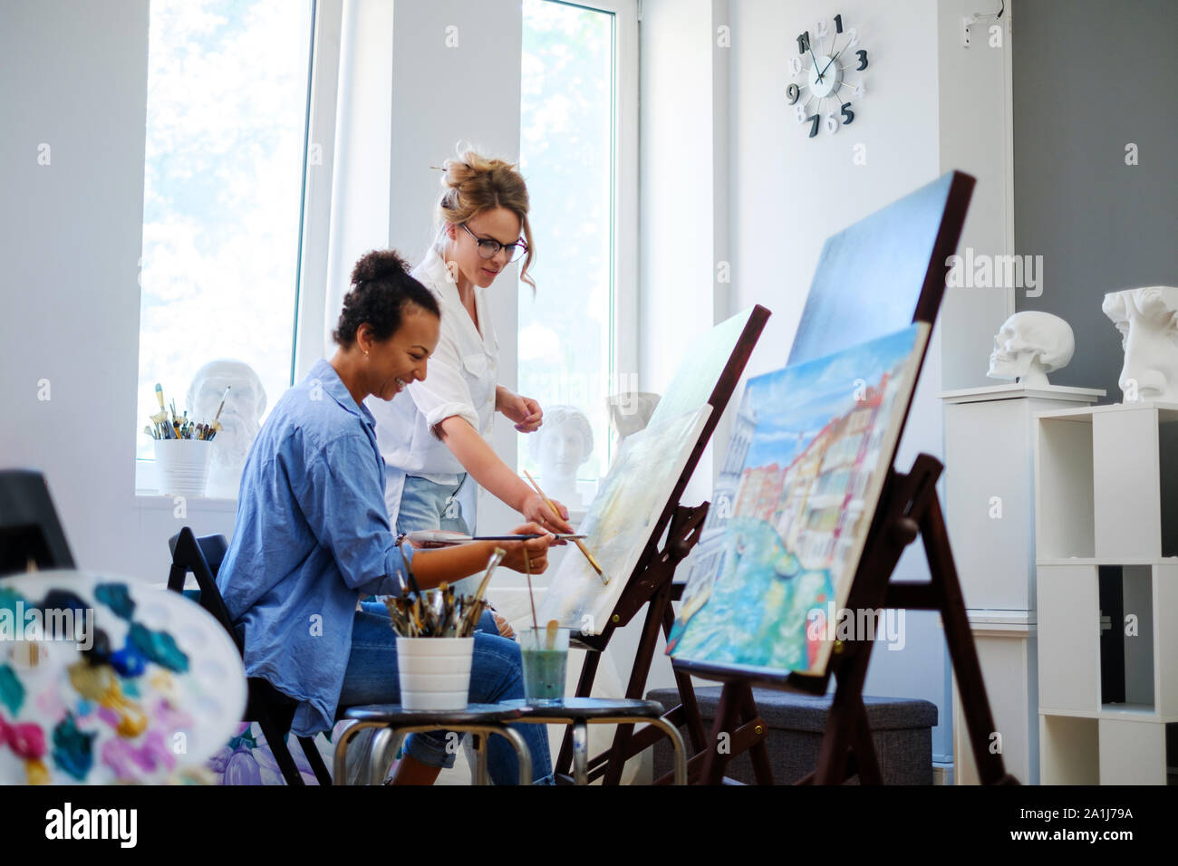 Creative painter and her protege working in a studio Stock Photo - Alamy