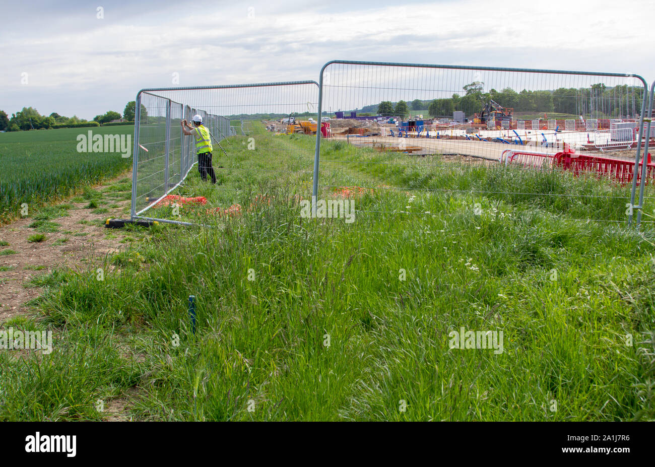 Worker completing fencing on a a green field building site Stock Photo ...