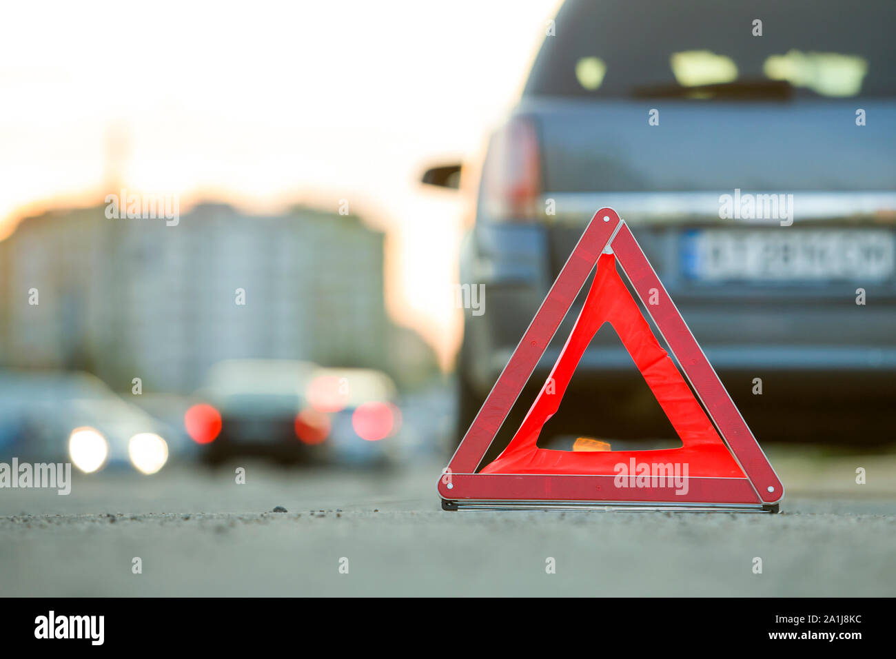 Red emergency triangle stop sign and broken car on a city street Stock ...