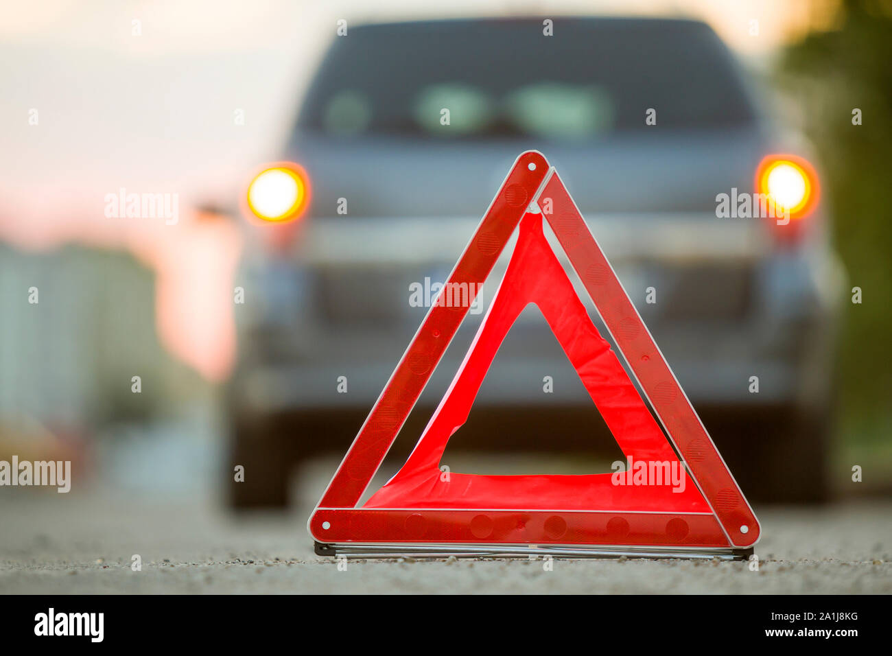 Red emergency triangle stop sign and broken car on a city street Stock ...