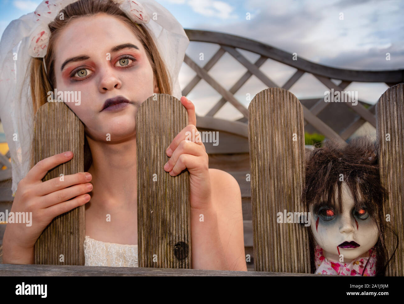 Terrified young bride and demon doll hide behind a fence Stock Photo ...
