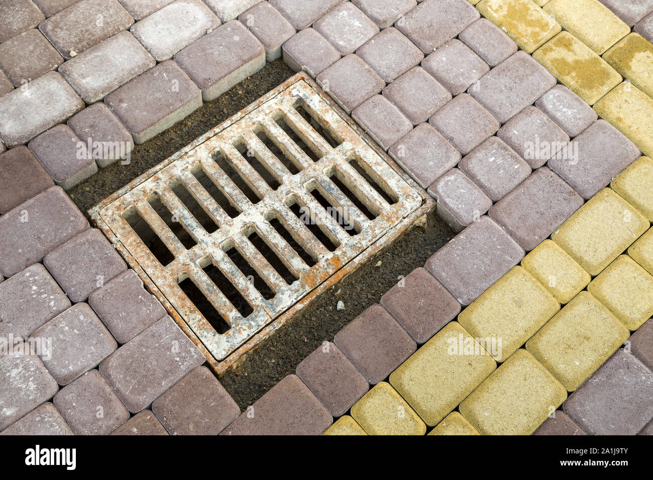Old rusted metal gutter for rain water on the stone paved sidewalk ...