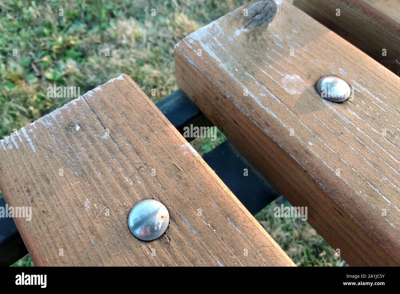 Close-up of wooden boards fastened with metal nails on a bench outdoors ...