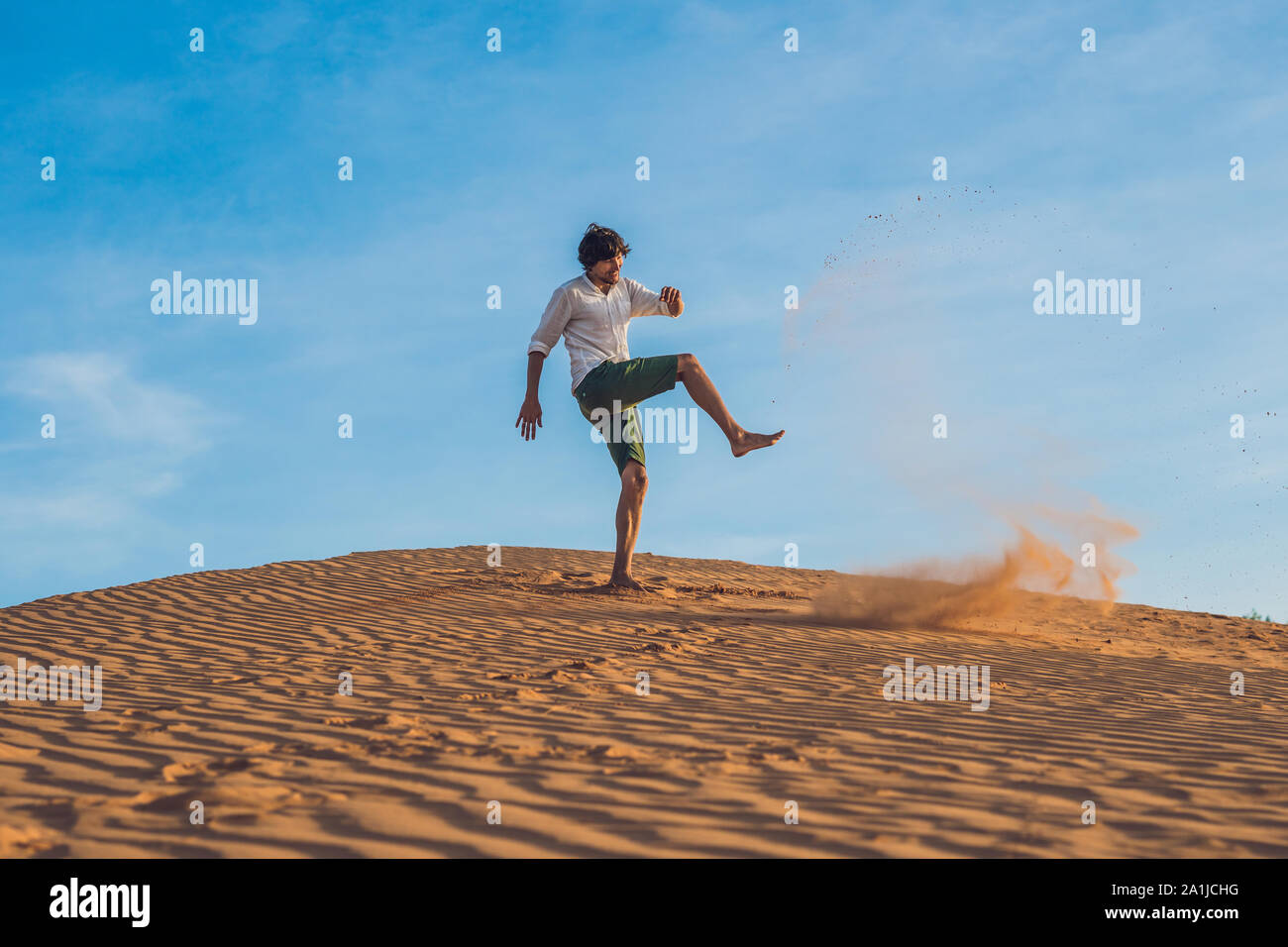 A man is kicking sand in a red desert. Splash of anger concept Stock ...