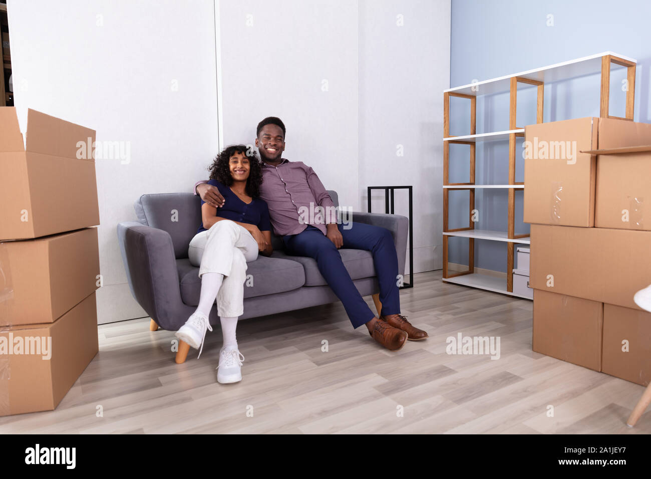 Young Couple Sitting On Couch Inside Their New Home Stock Photo - Alamy