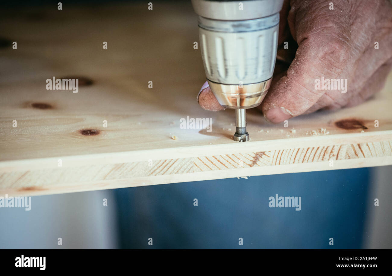 Craftsman is drilling in wood with drilling machine Stock Photo - Alamy