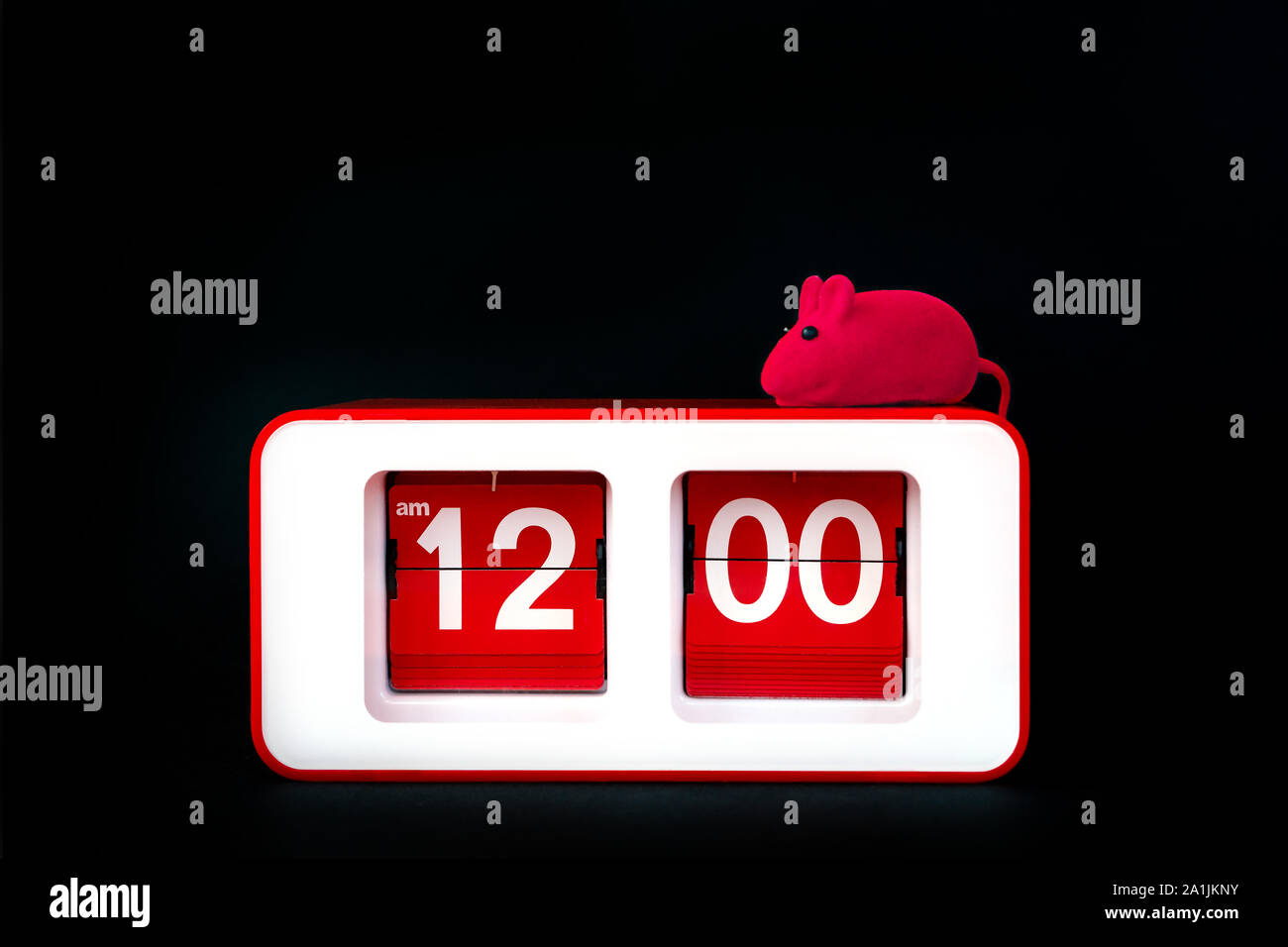 A red rectangular clock on a black background and a small toy rat Stock ...