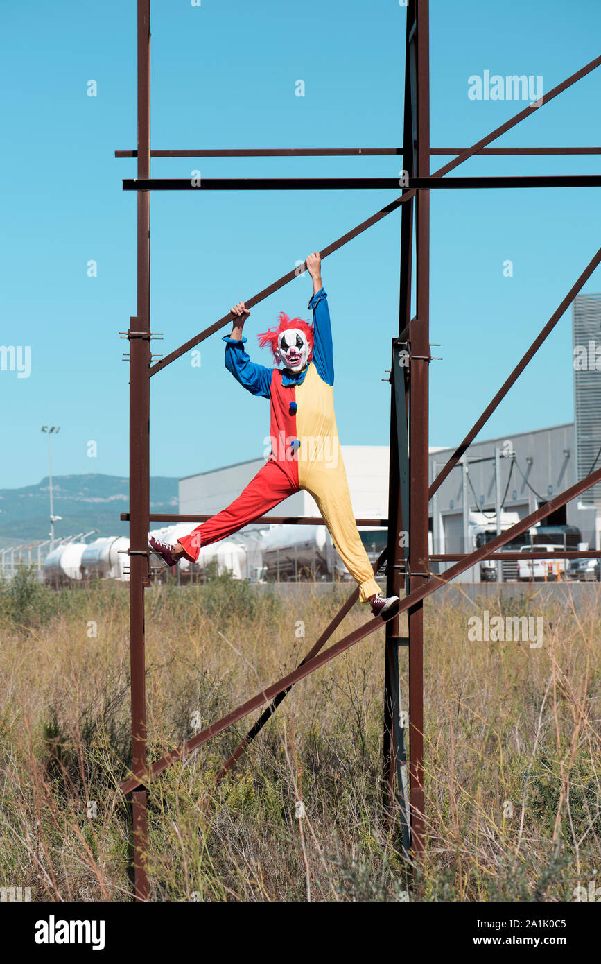a scary evil clown wearing a colorful yellow, red and blue costume ...