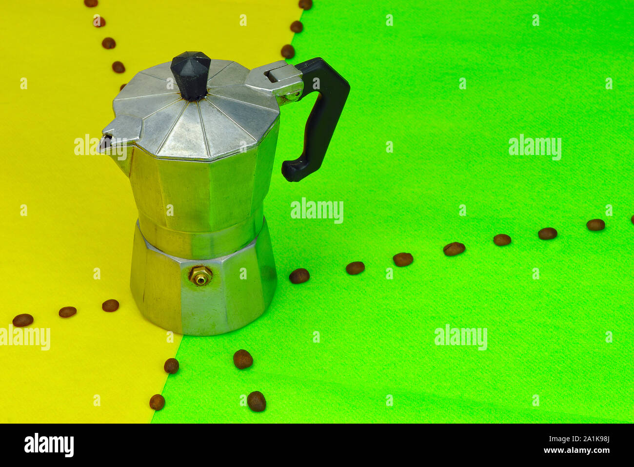 small traditional italian coffee pot on green and yellow background ...