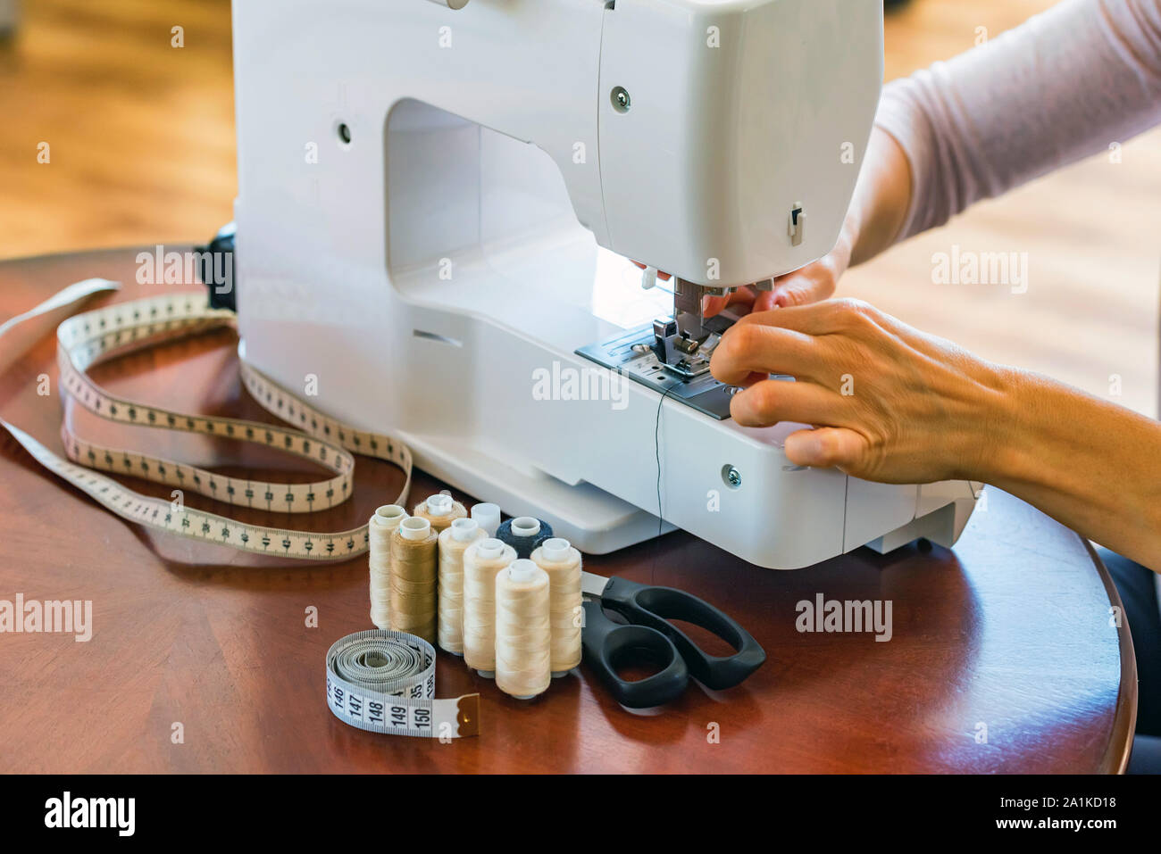 Dressmaker or seamstress works using sewing machine. Reels, scissors ...
