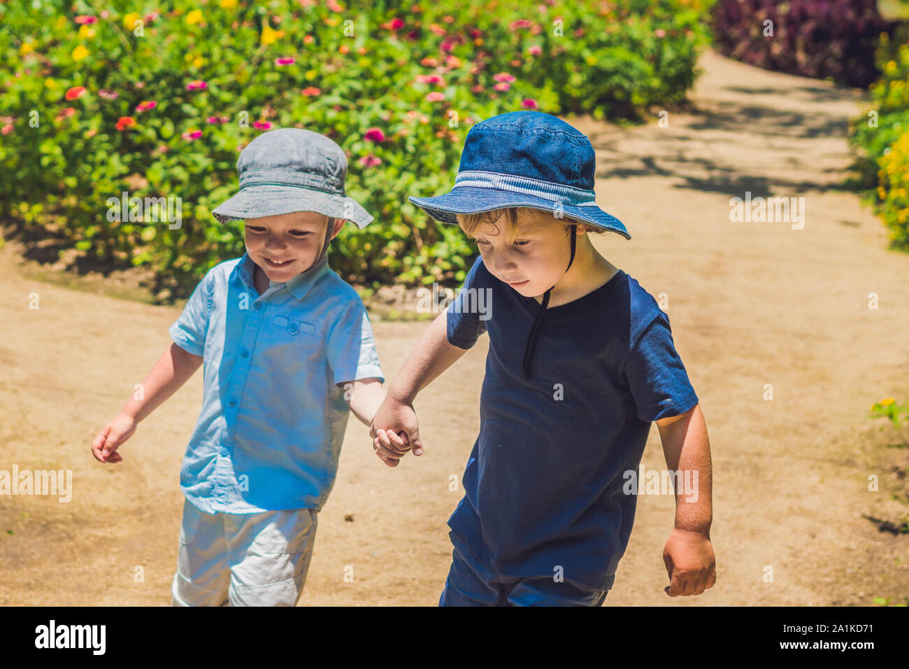 Two happy brothers running together on a park path in a tropical park ...