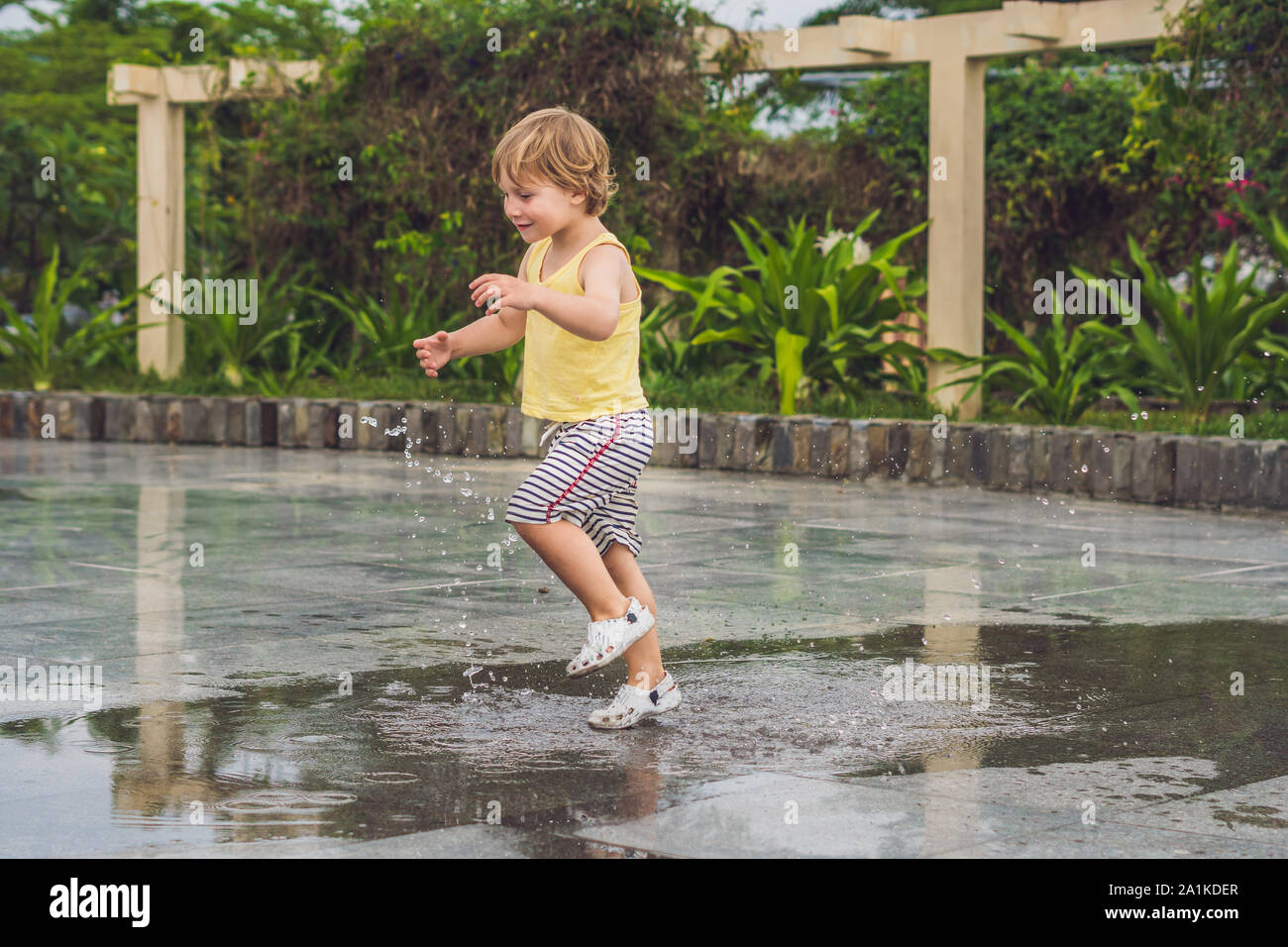 Child splashing through a puddle hi-res stock photography and images ...