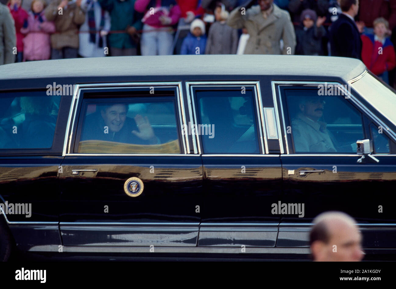 New president George H.W. Bush, in presidential automobile, waves to ...
