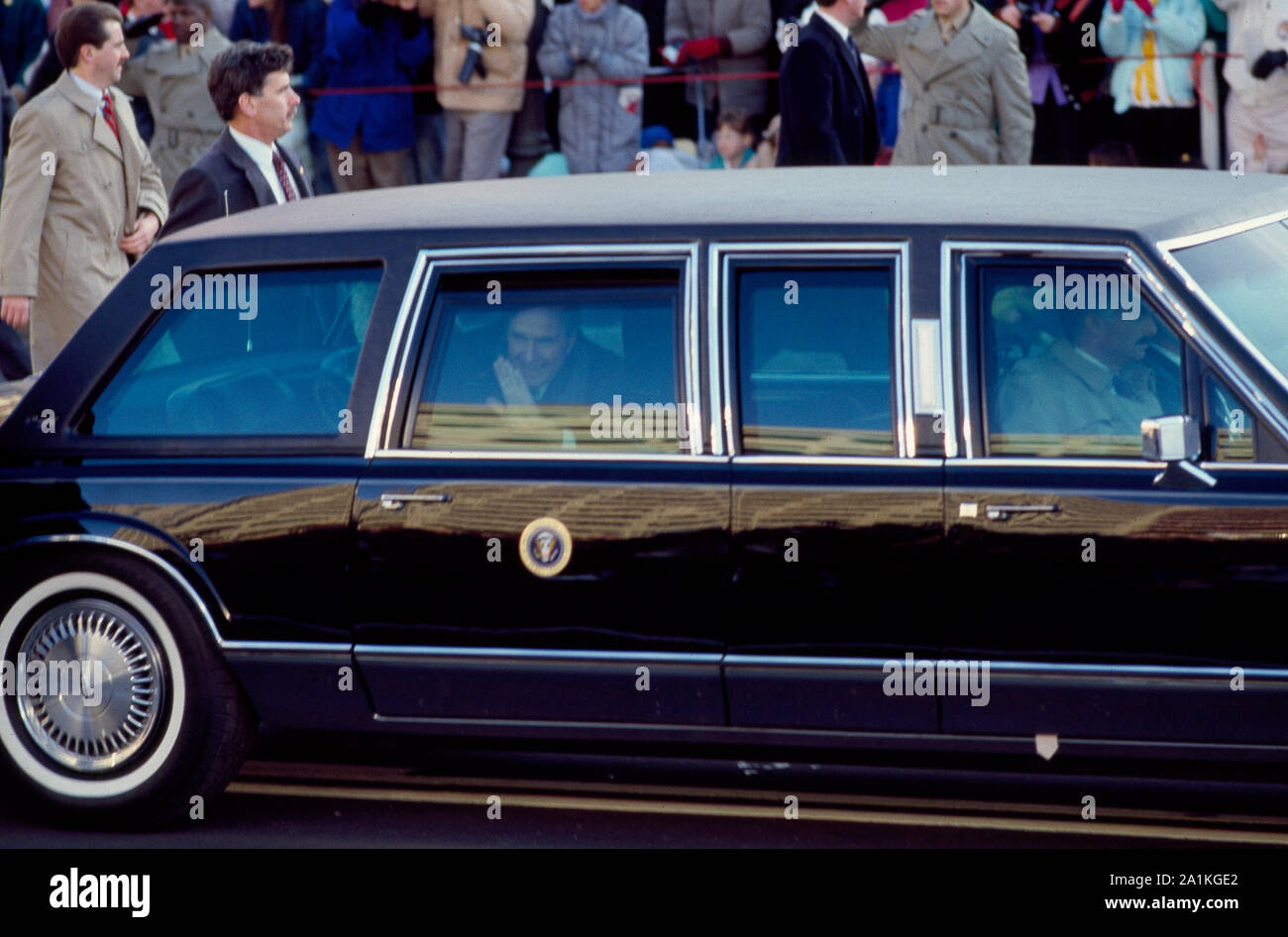 New president George H.W. Bush, in presidential automobile, waves to ...
