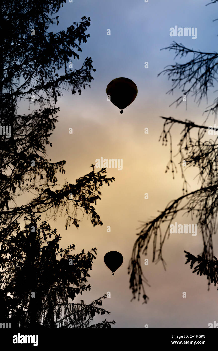 Two hot air balloons hovers in the cloudy sky. Sunset. In the ...