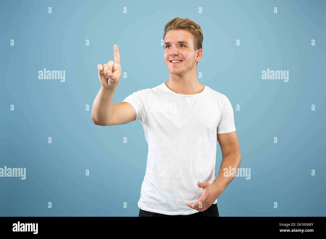 Caucasian young man's half-length portrait on blue studio background ...