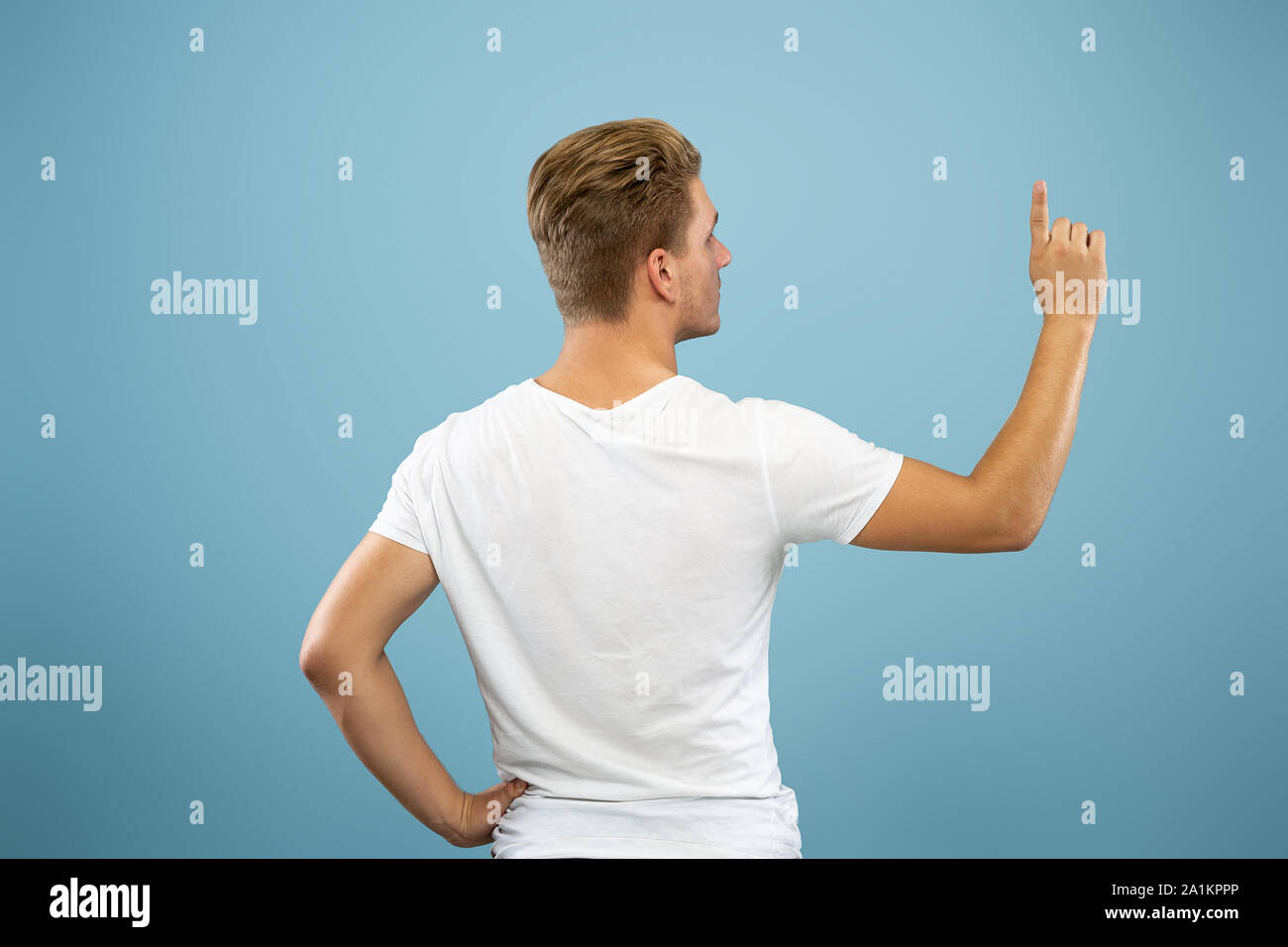 Caucasian young man's half-length portrait on blue studio background ...