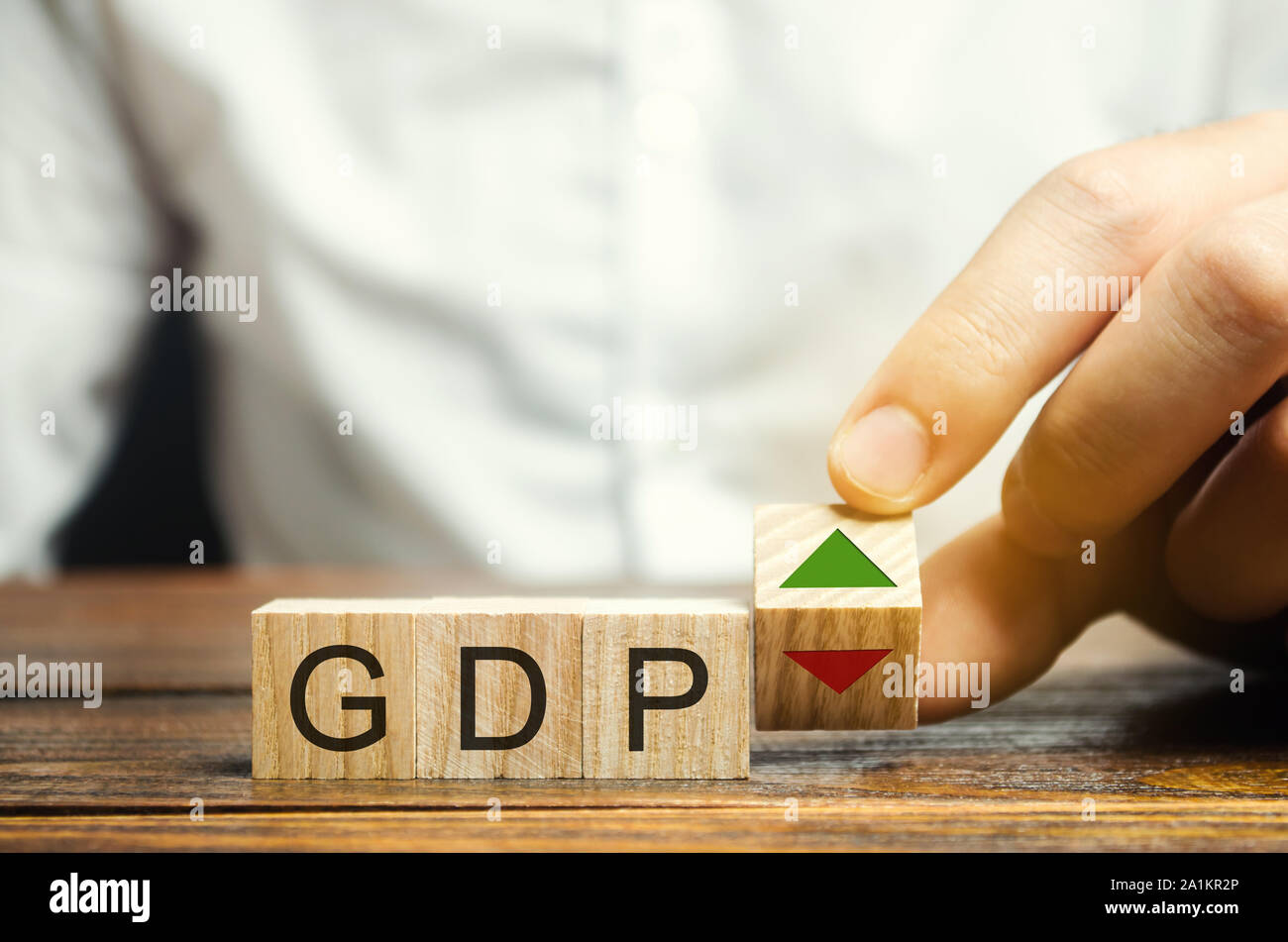 Wooden blocks with the word GDP and up and down arrows. An unstable ...