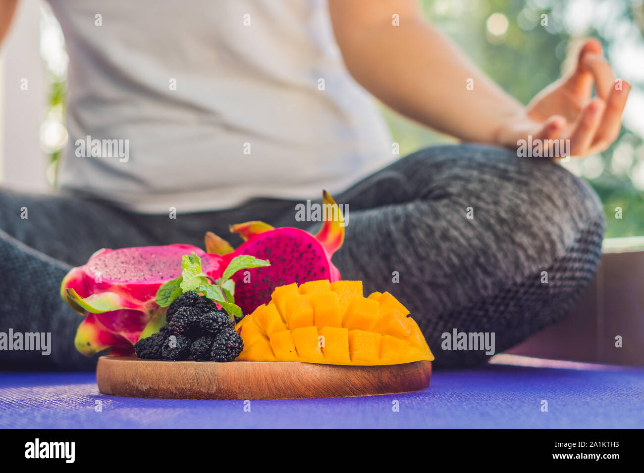 hand of a woman meditating in a yoga pose, sitting in lotus with fruits in front of her dragon ...