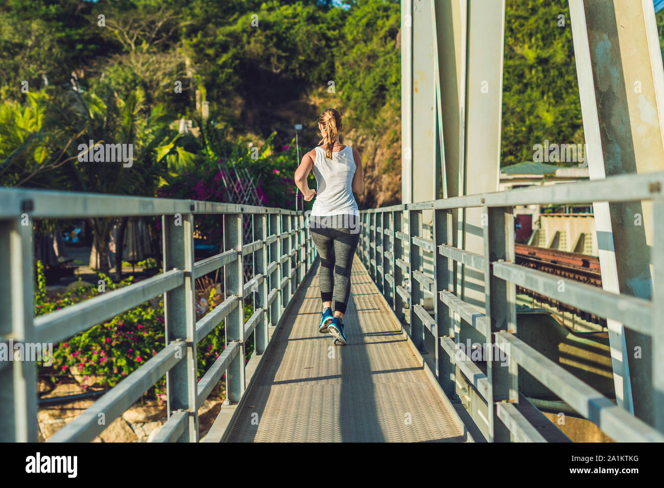 Beautiful woman running over bridge during sunset Stock Photo - Alamy