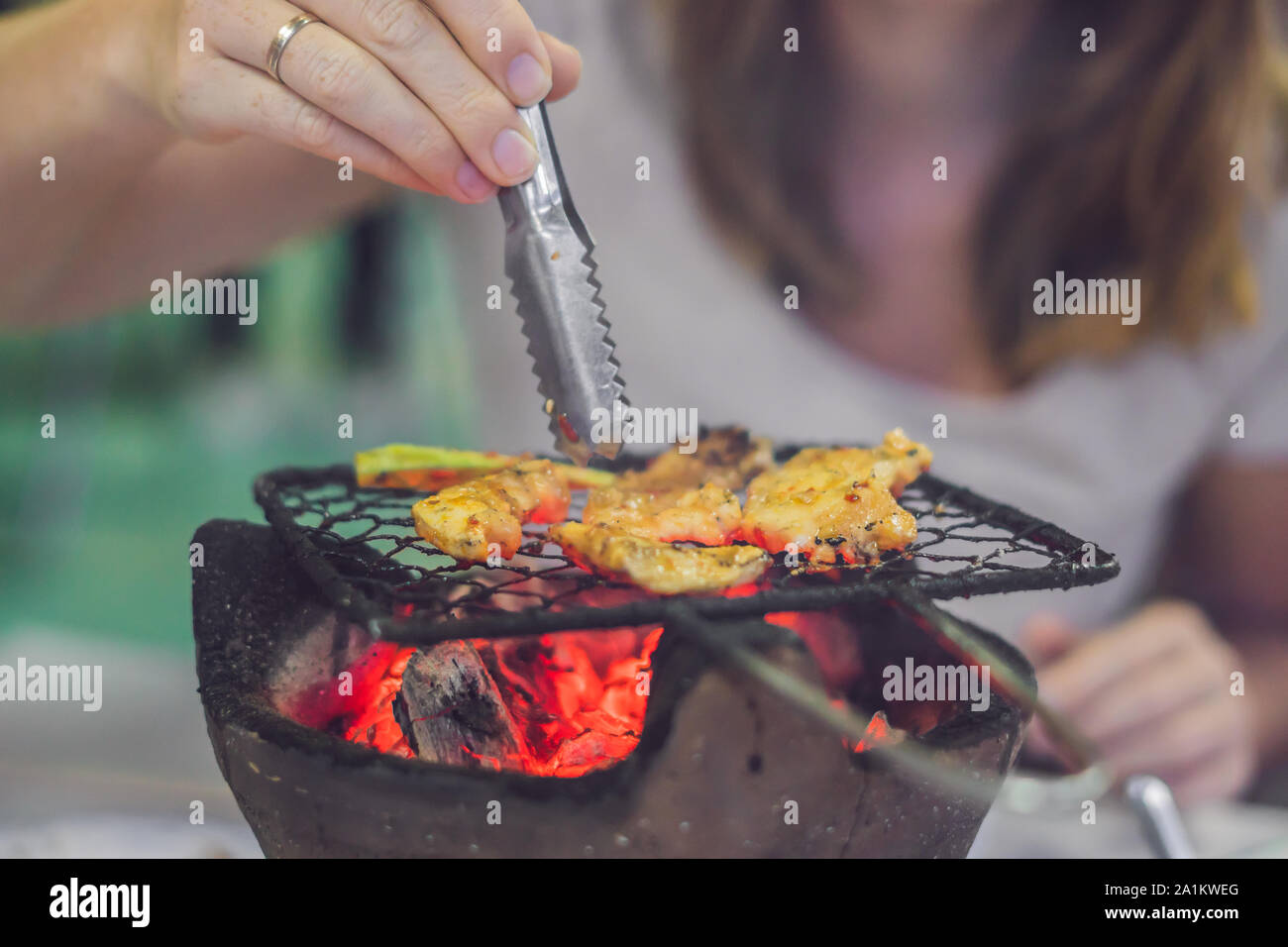 Girl frying meat on a small grill in a restaurant Stock Photo - Alamy