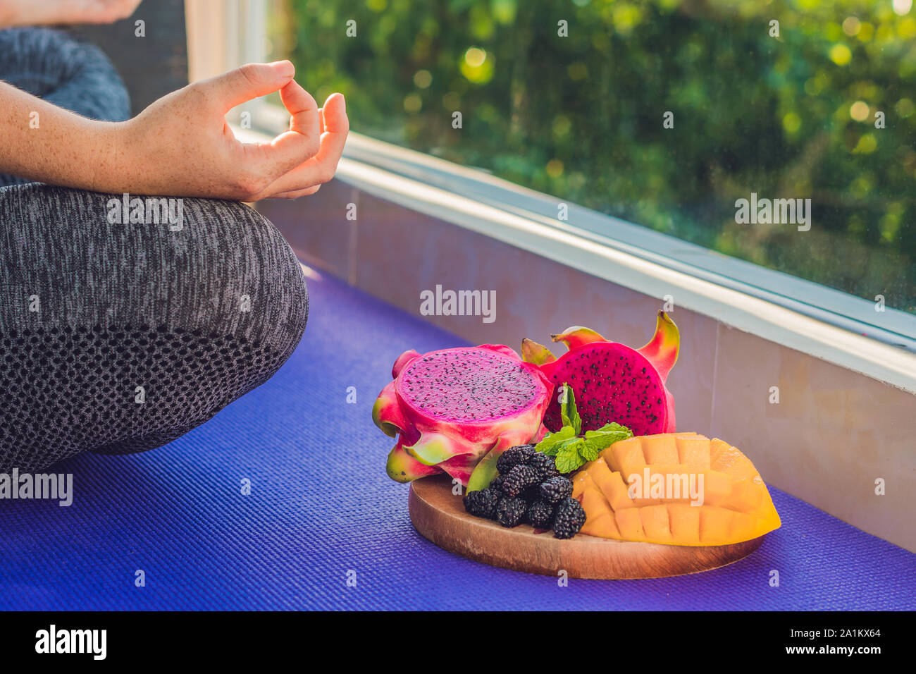 hand of a woman meditating in a yoga pose, sitting in lotus with fruits in front of her dragon ...