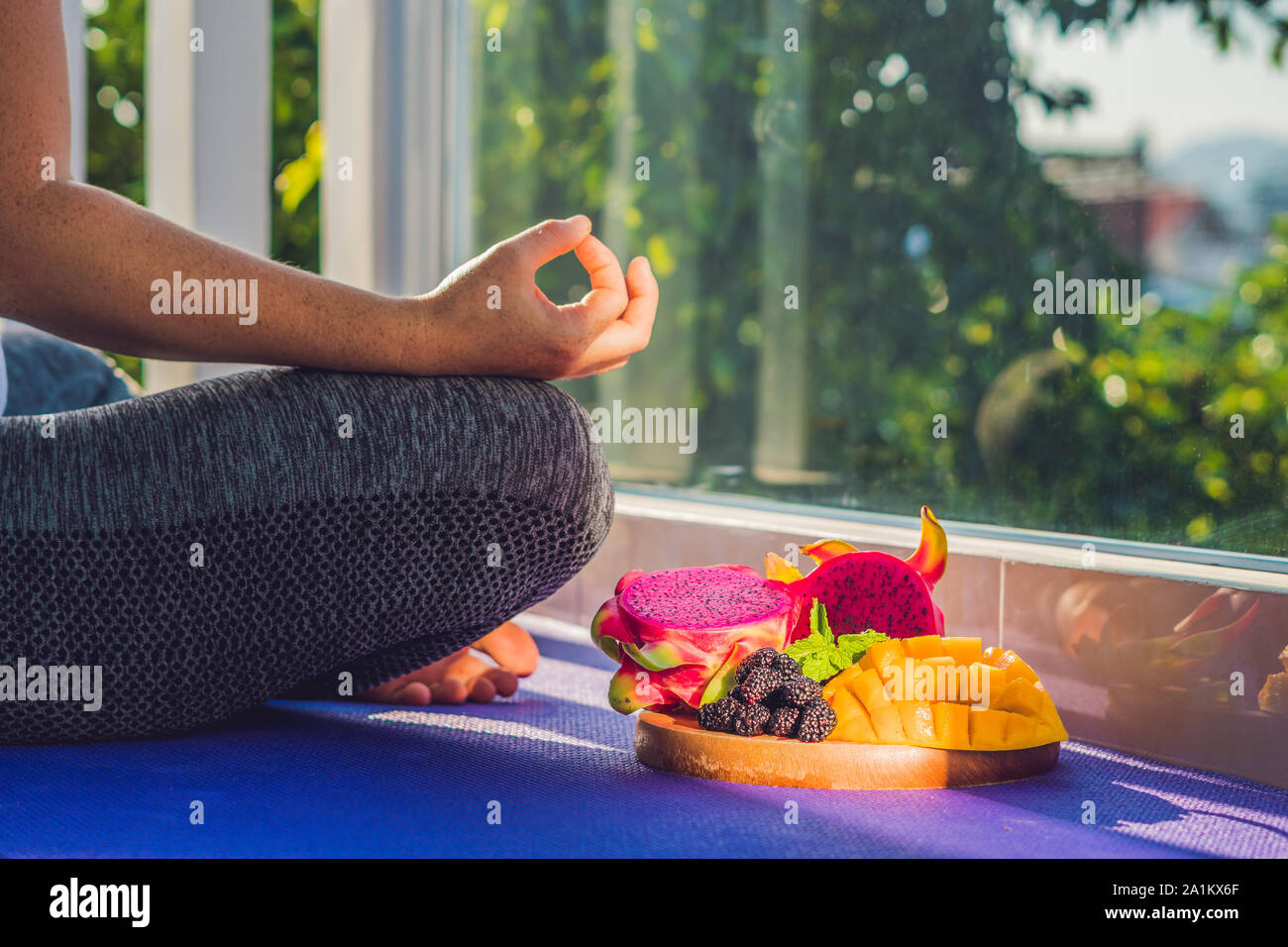 hand of a woman meditating in a yoga pose, sitting in lotus with fruits in front of her dragon ...
