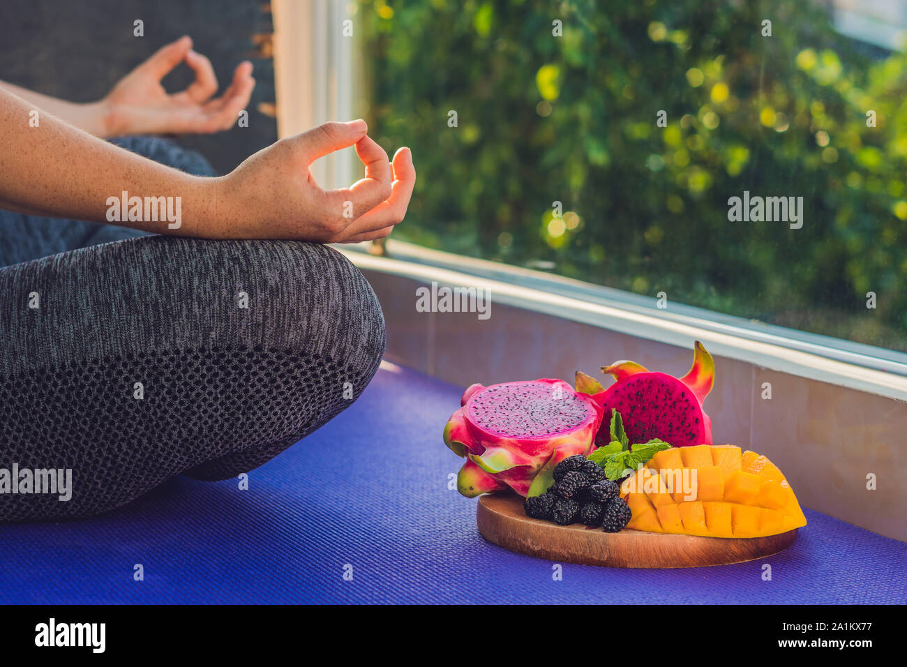 hand of a woman meditating in a yoga pose, sitting in lotus with fruits in front of her dragon ...
