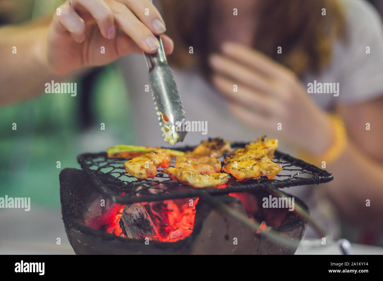 Girl frying meat on a small grill in a restaurant Stock Photo - Alamy