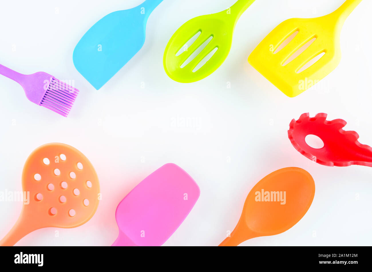 bright multi colored kitchen utensils on white background with copy ...
