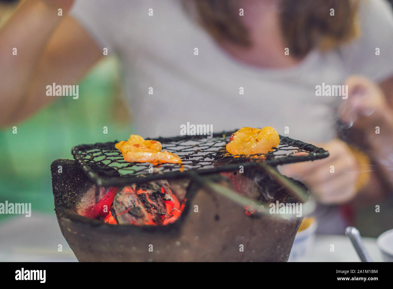 Girl frying meat on a small grill in a restaurant Stock Photo - Alamy