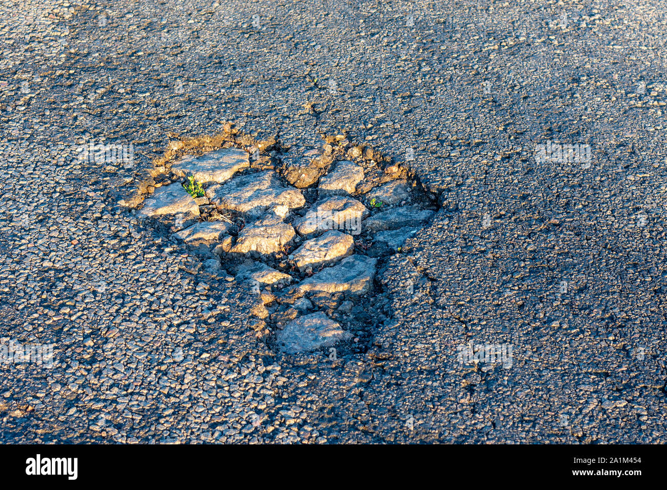 pothole on asphalt closeup with blue and gray stones. Background ...