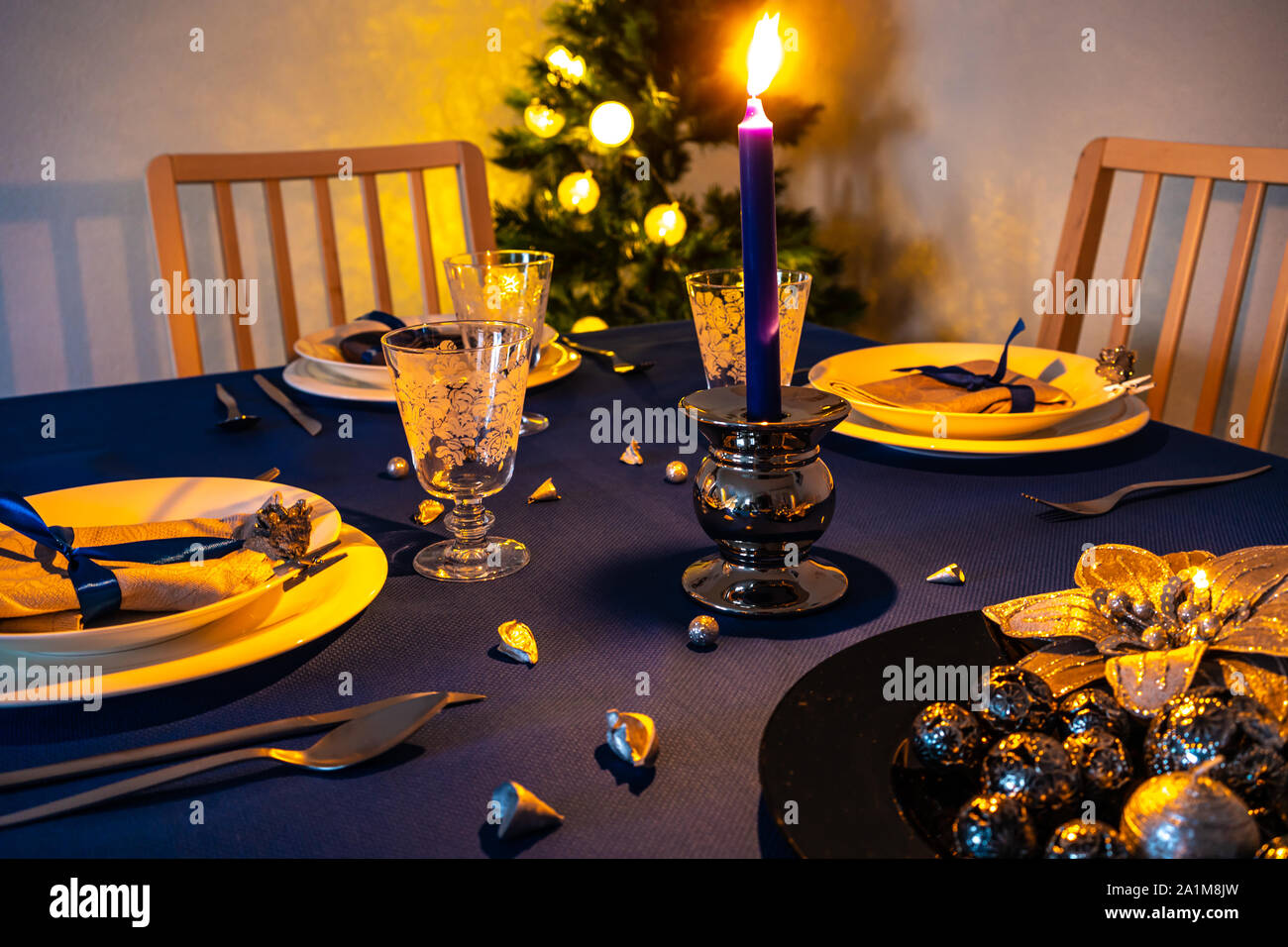 Christmas table setting with christmas tree in background at candle ...