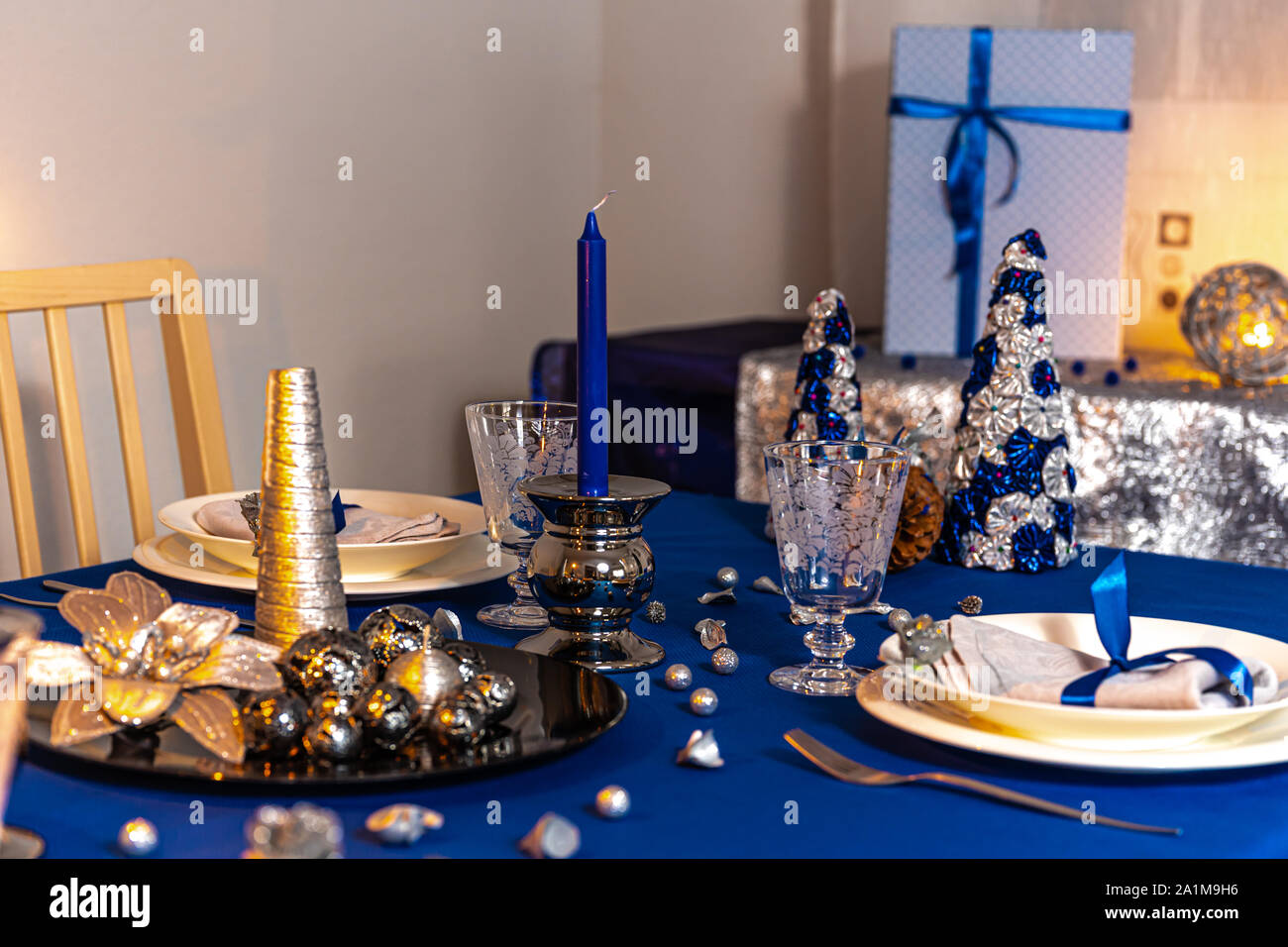 Christmas table decoration with wrapped gifts in background at candle ...