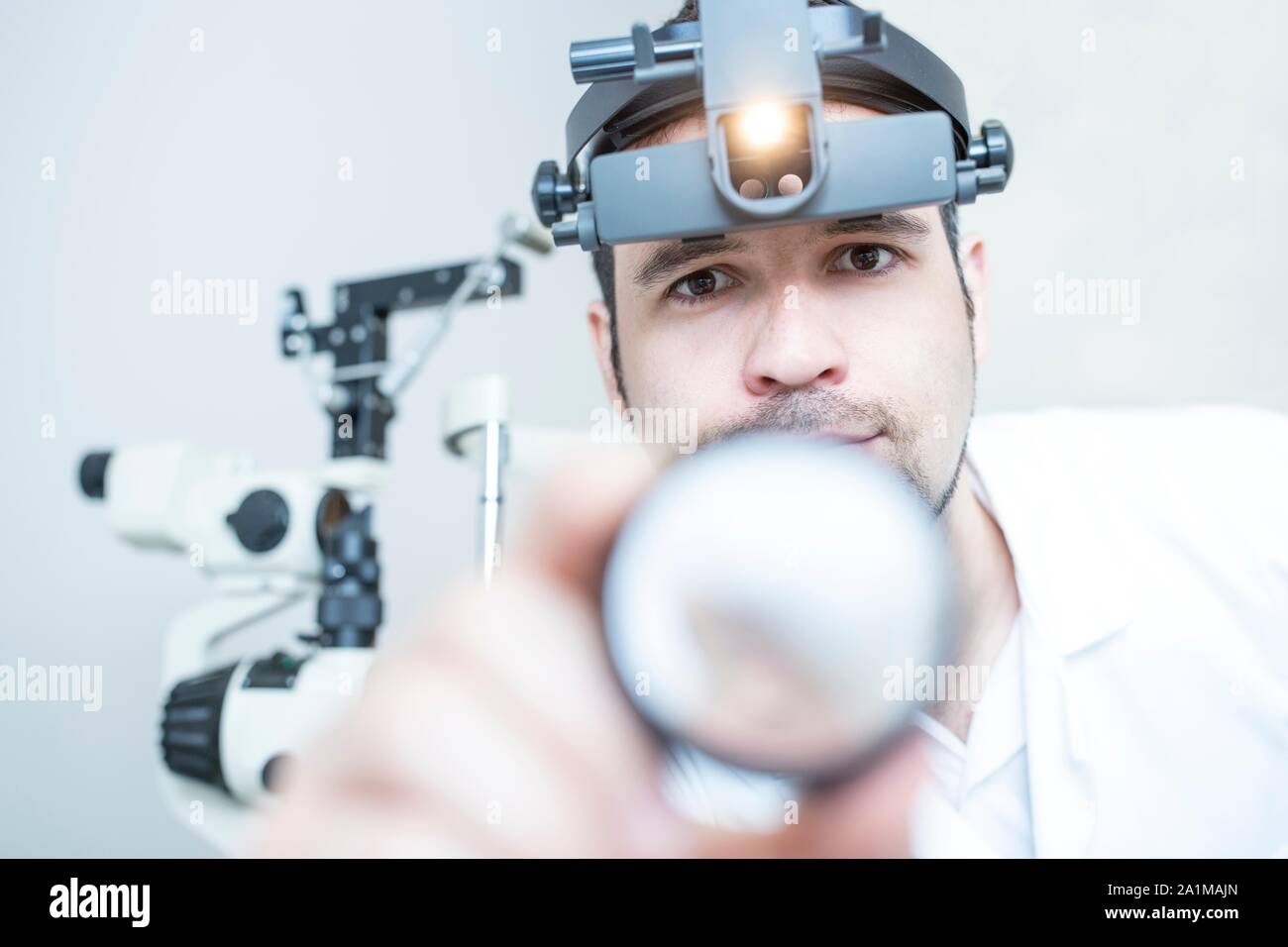 Indirect ophthalmoscope eye examination. Ophthalmologist using a head ...