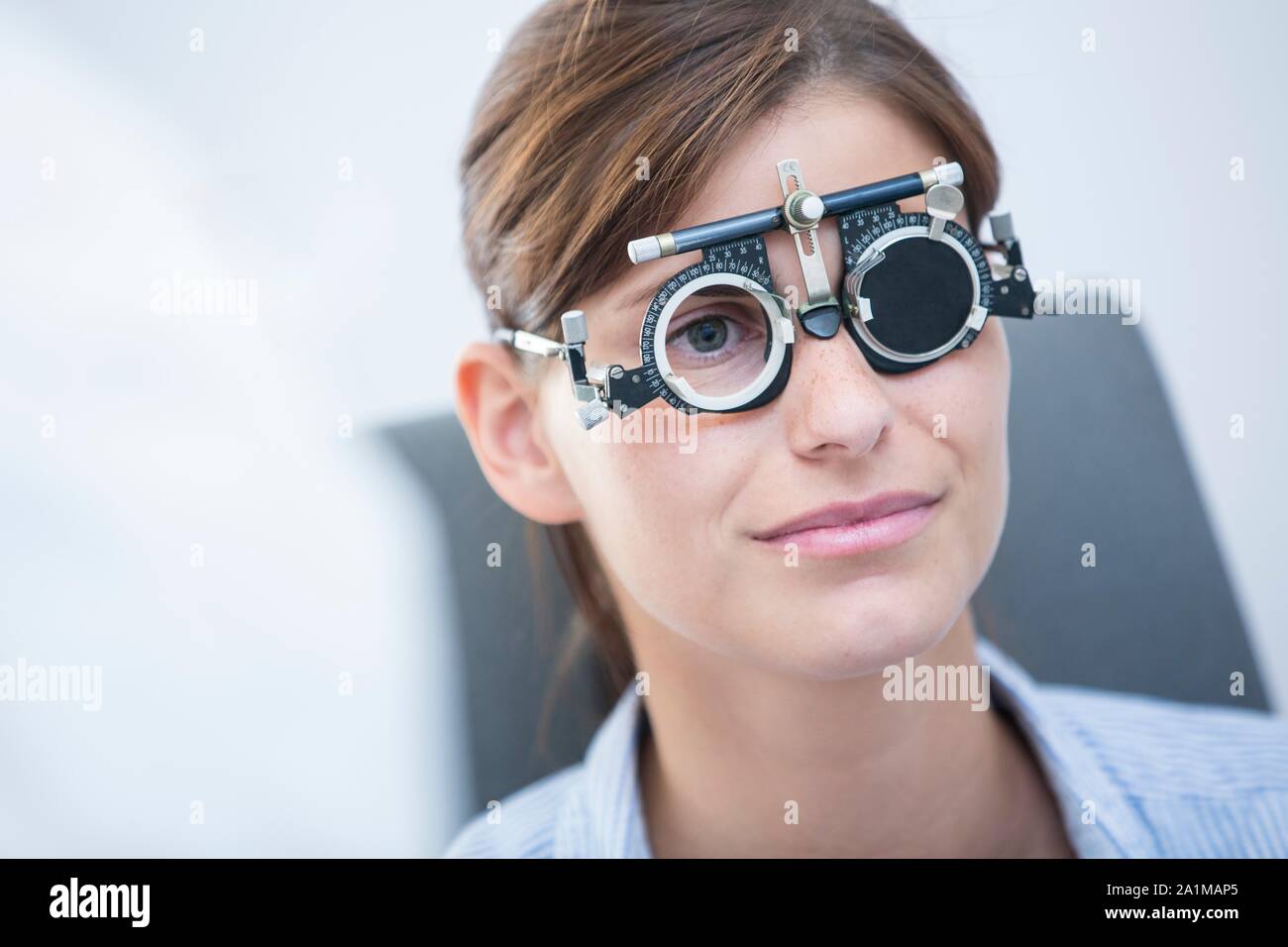 Eye examination. Woman wearing trial frames during an eye examination ...