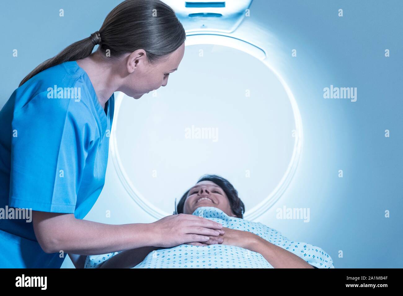 Radiographer comforting patient before computed tomography (CT) scan ...