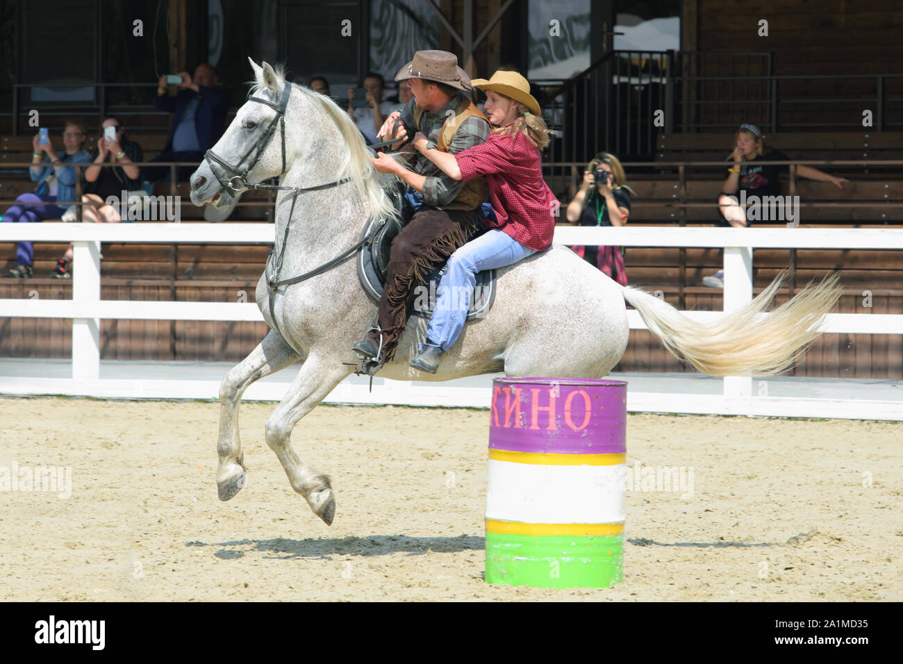 Female cowgirl and cowboy performing in barrel racing event with horse ...