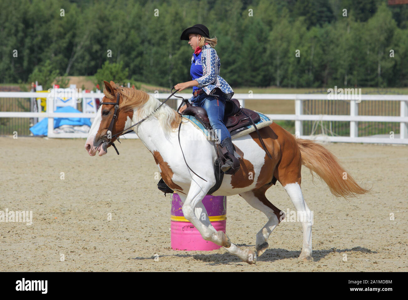 Female cowgirl and cowboy performing in barrel racing event with horse ...