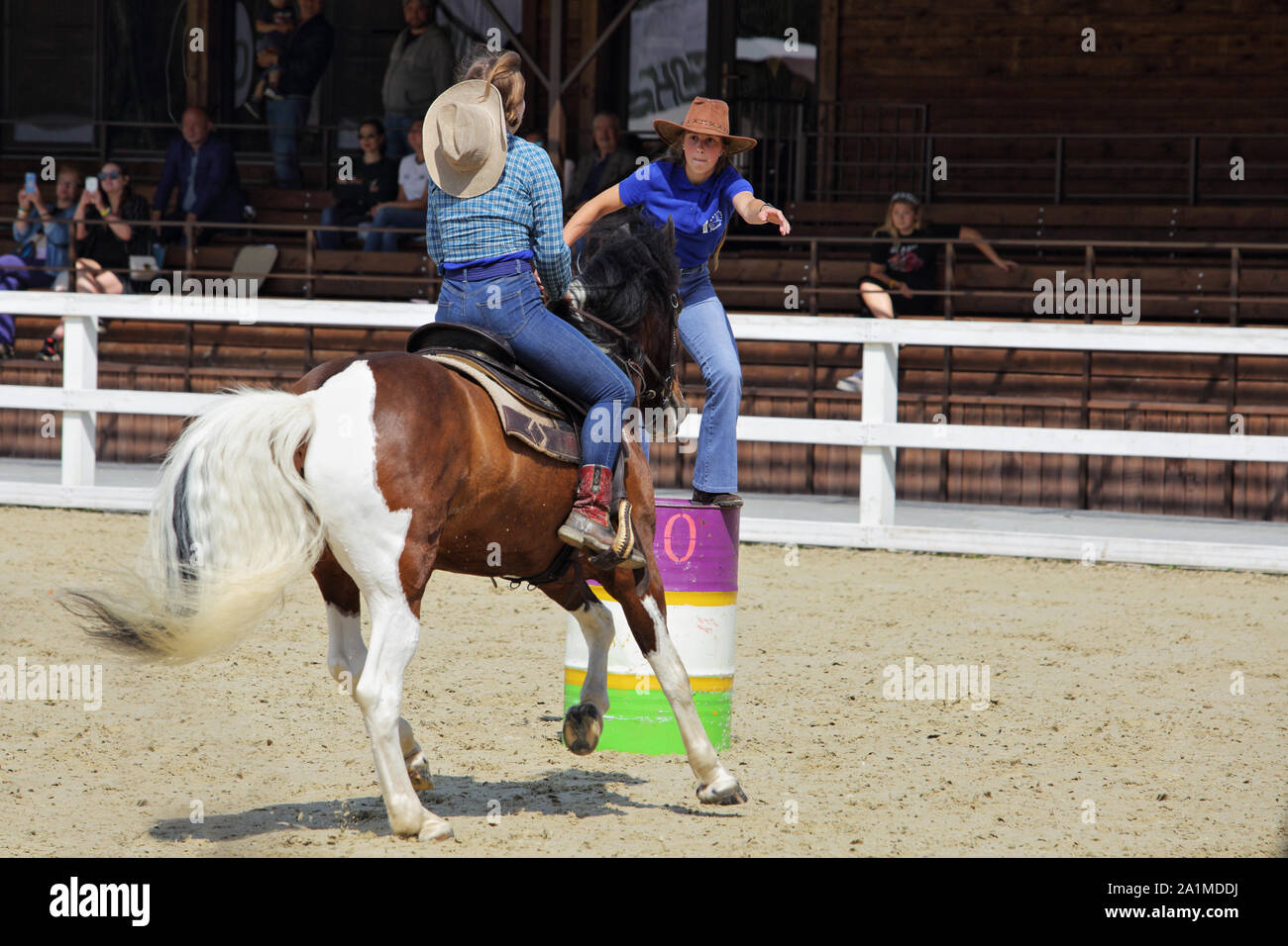 Female cowgirl and cowboy performing in barrel racing event with horse ...