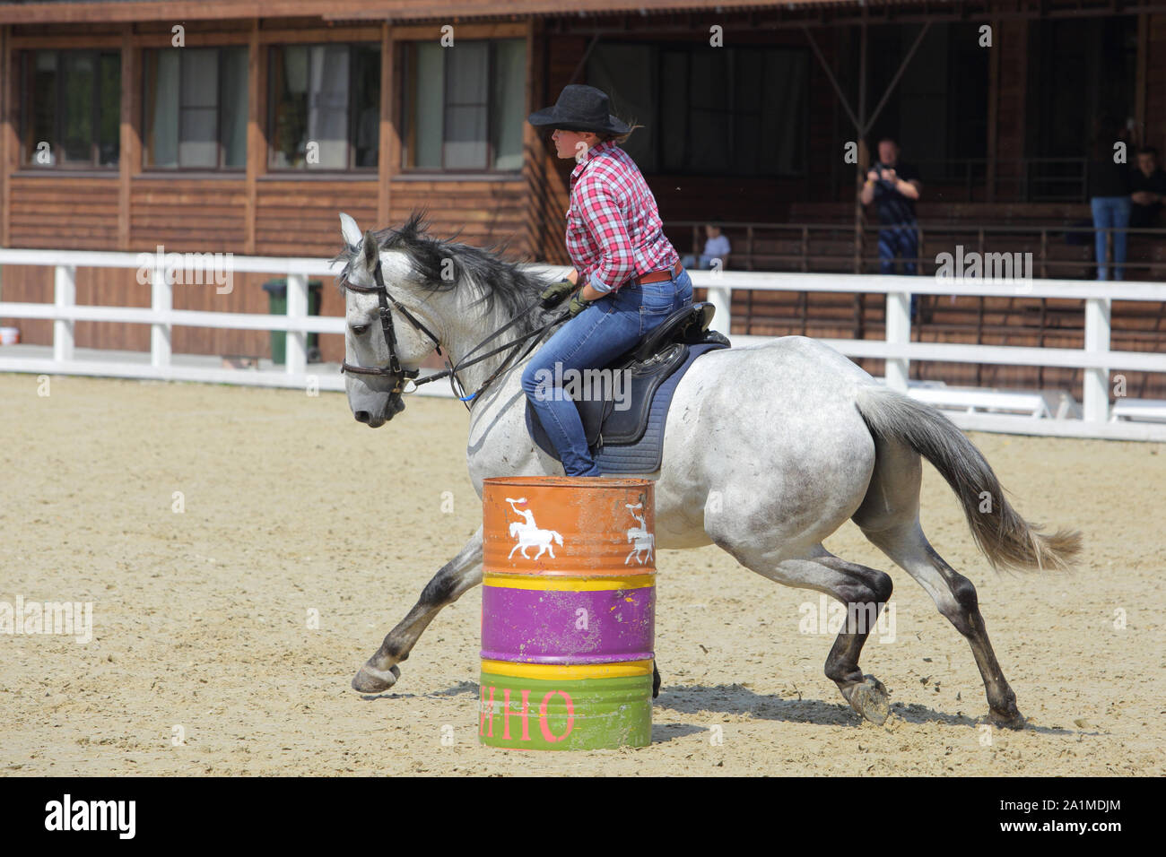 Female cowgirl and cowboy performing in barrel racing event with horse ...