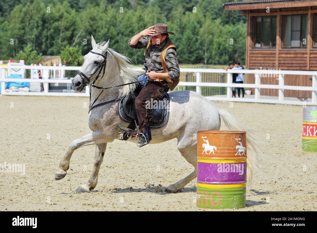 Female cowgirl and cowboy performing in barrel racing event with horse ...