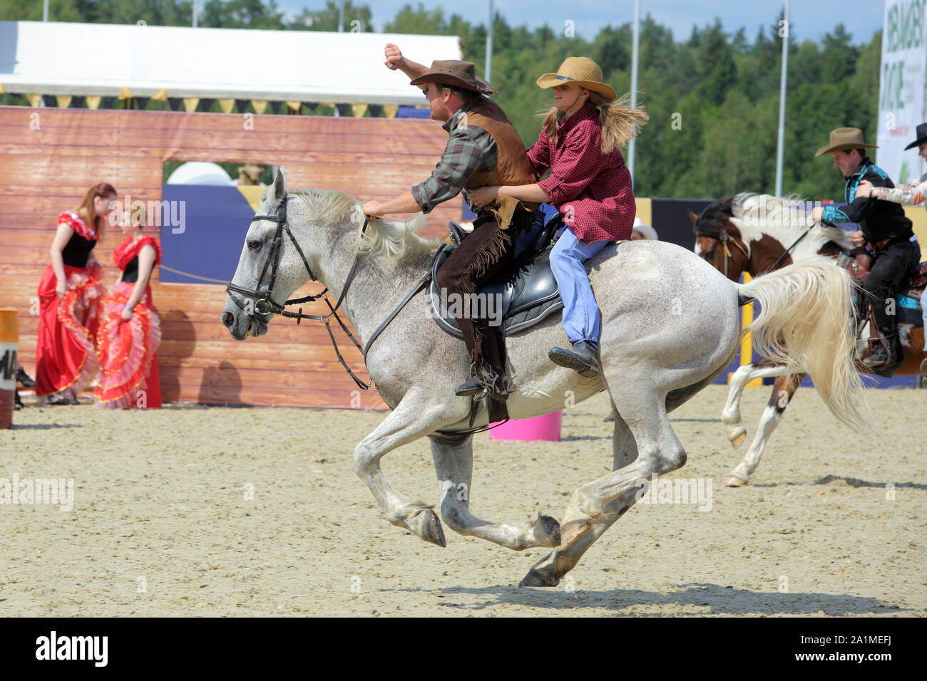Female cowgirl and cowboy performing in barrel racing event with horse ...