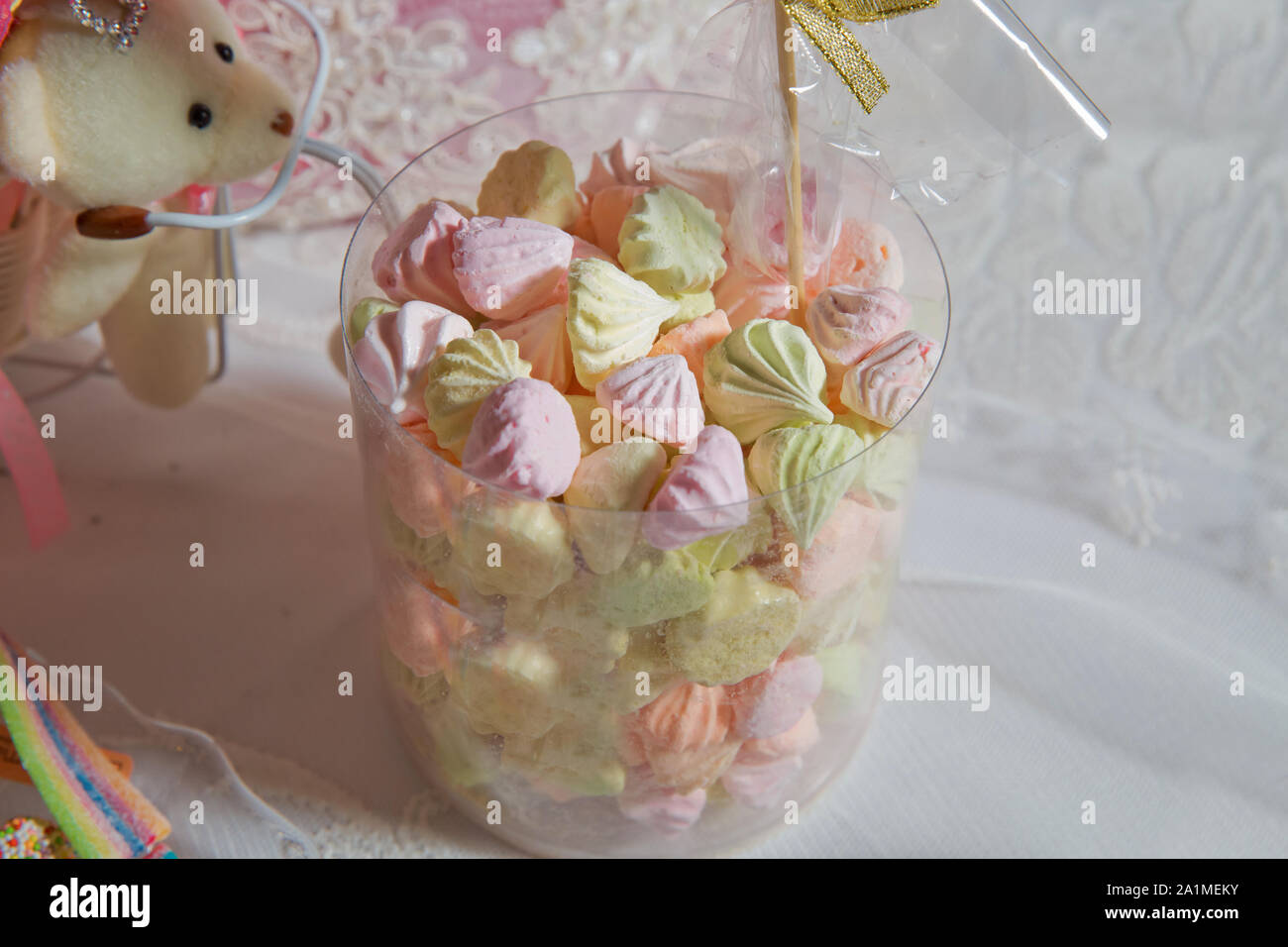 colorful marshmallow candies in plastic container on a white background ...