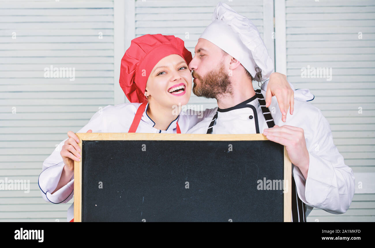 Man and woman chef cooking food together. Couple with blackboard for ...