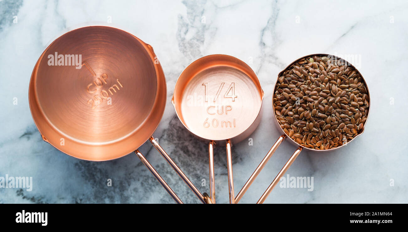 Copper measuring cups on marble table in the kitchen. Ready to cook or ...