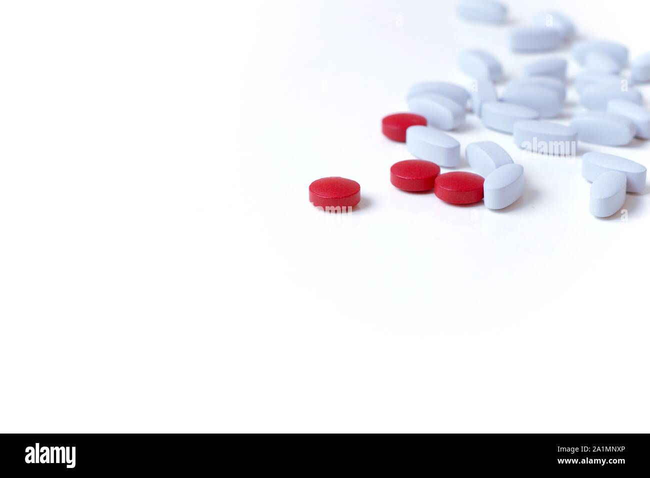 Single red pill shown prominently among light blue pills on white ...